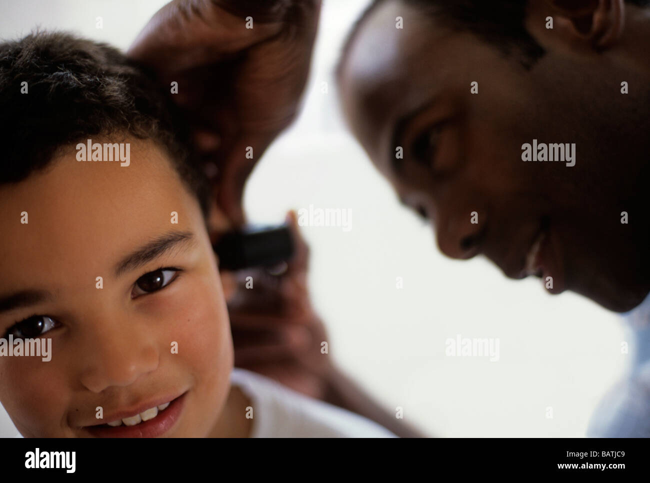 Ear examination. General practice doctor examining a 9-year-old boy's ...