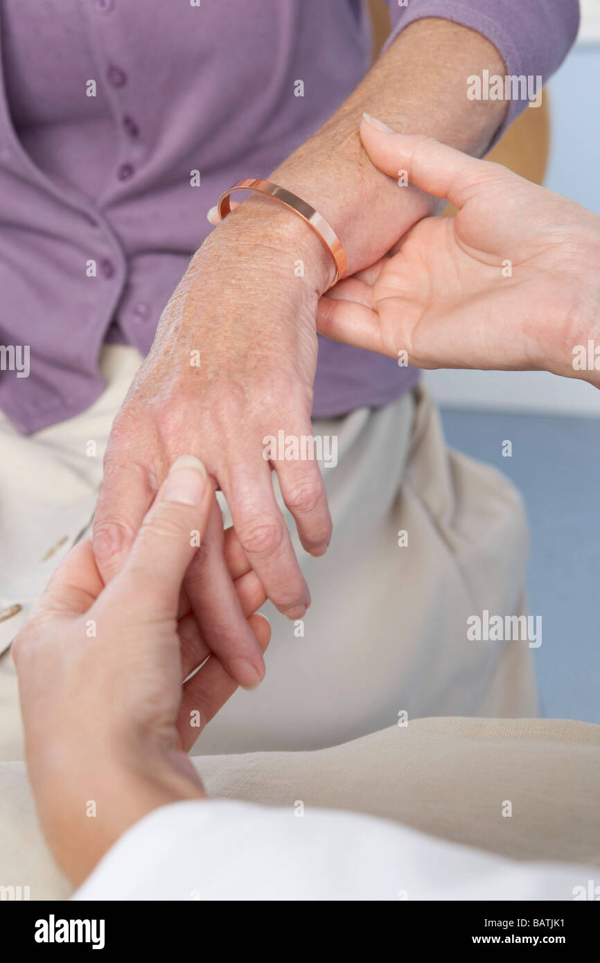 Rheumatoid arthritis.General practitioner examining a patient's hand ...