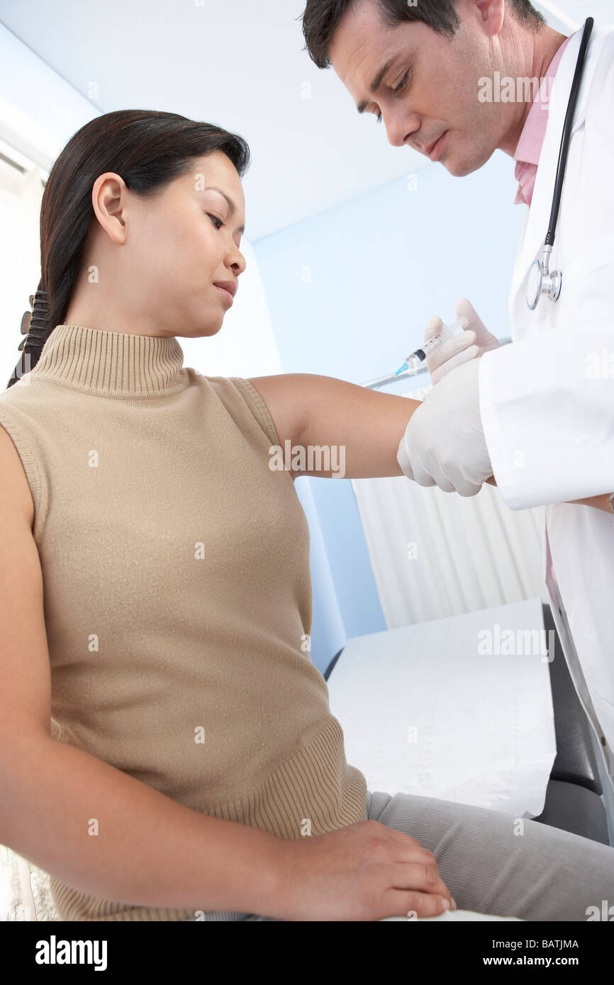 Injection. Doctor administering an injection to a patient's arm Stock ...