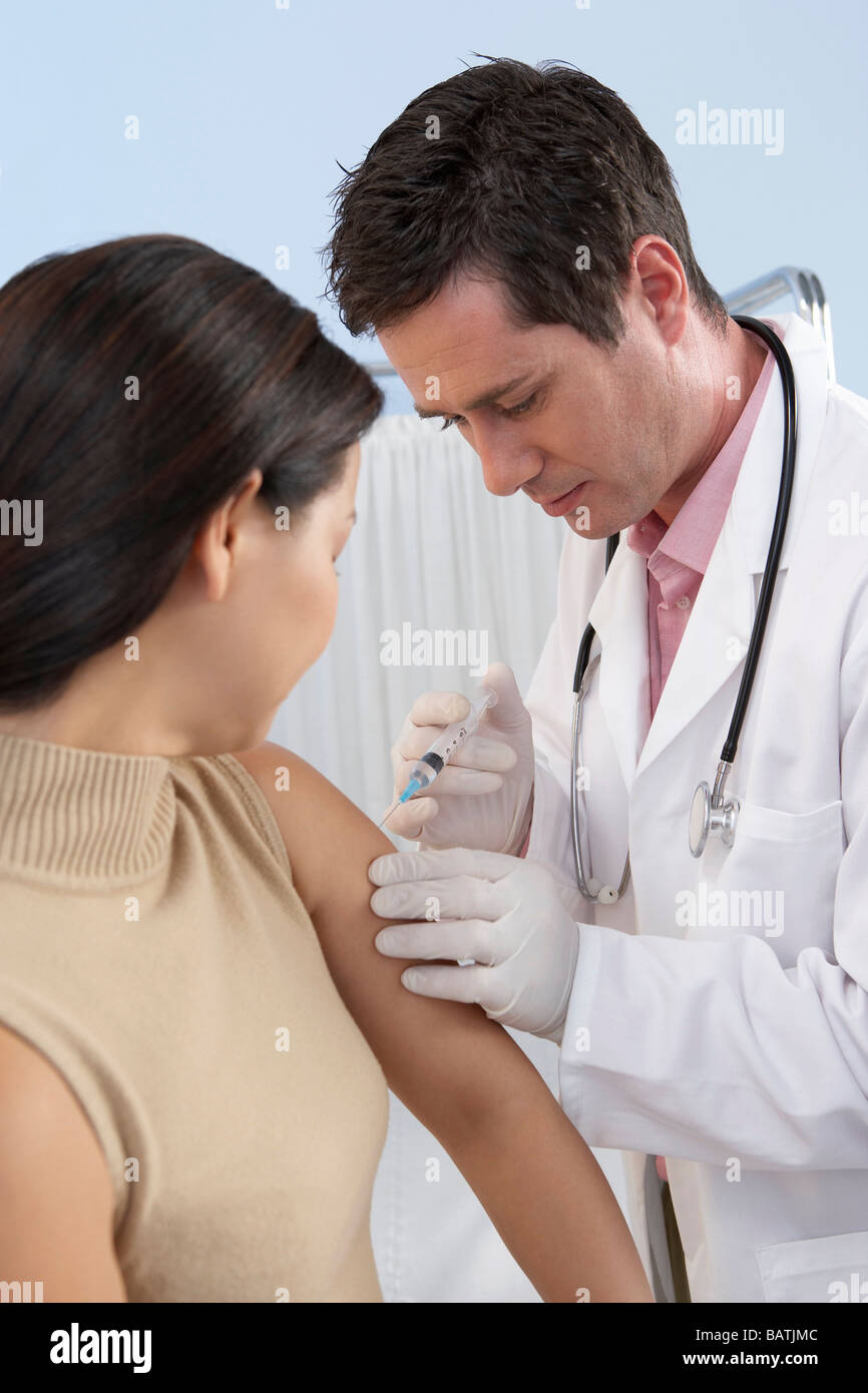 Injection. Doctor administering an injection to a patient's arm Stock ...