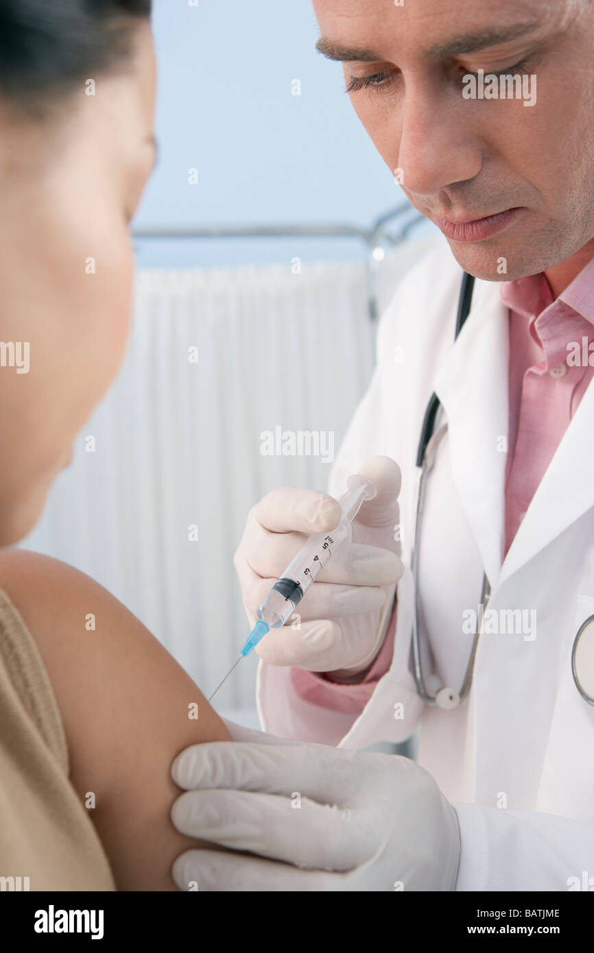 Injection. Doctor administering an injection to a patient's arm Stock ...