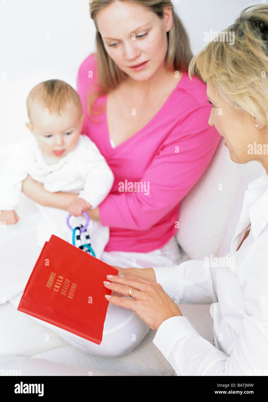 Child health record. Health visitor showing a child health record to a ...
