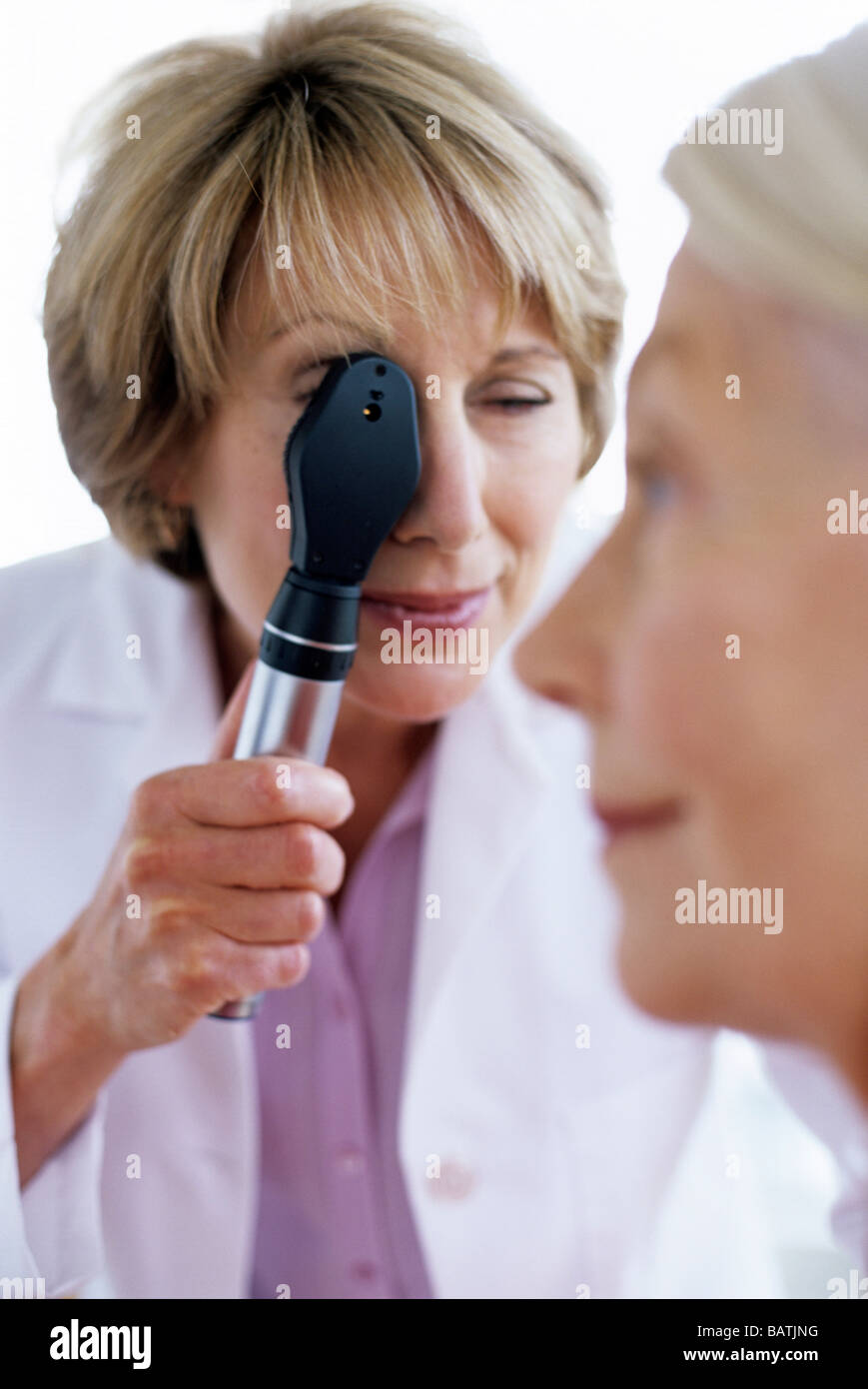 Eye examination. General practice doctor examining a 63-year-old woman ...
