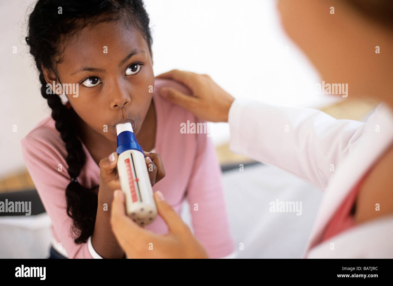Lung fucntion test. Nine year old girl breathing into a peak flow meter ...