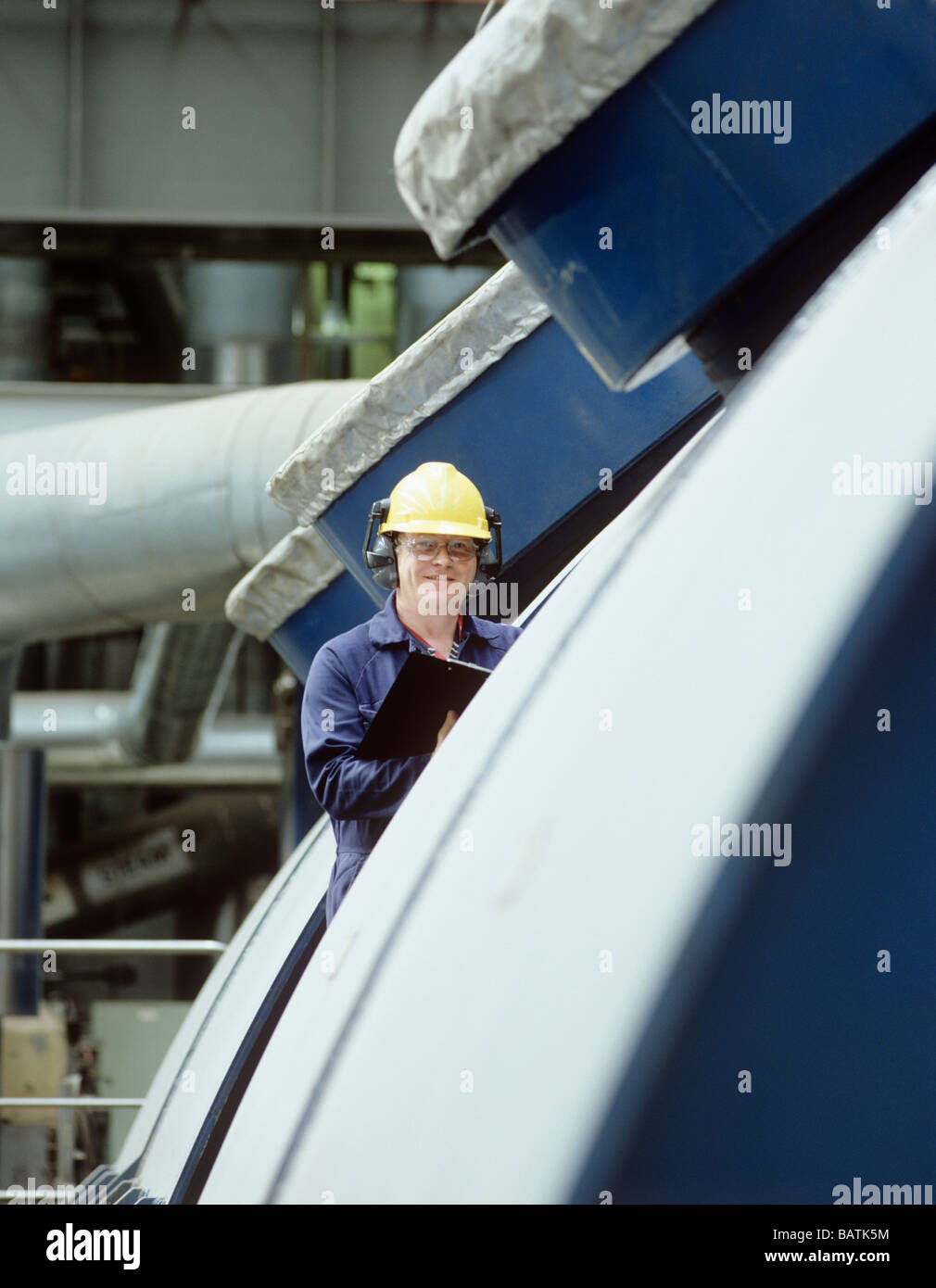 Power station. Worker nextto a turbine in a gas fired power station ...