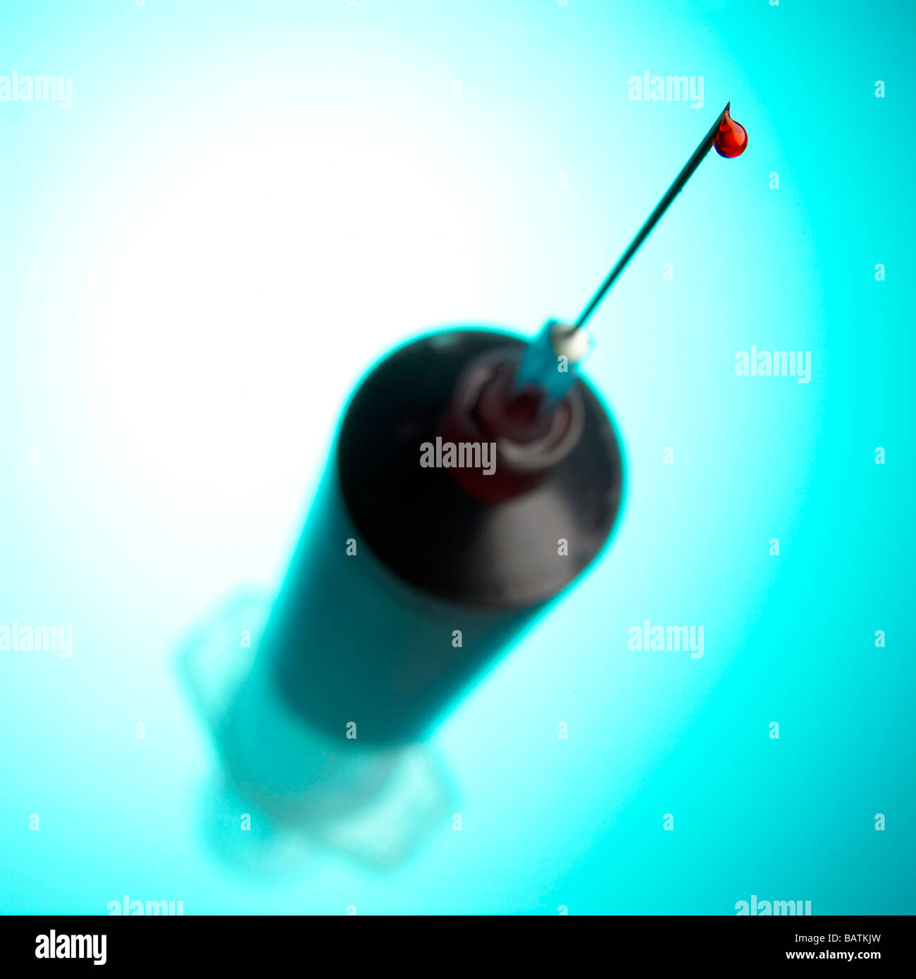 Blood filled syringe with a drop of blood on the tip of the needle ...