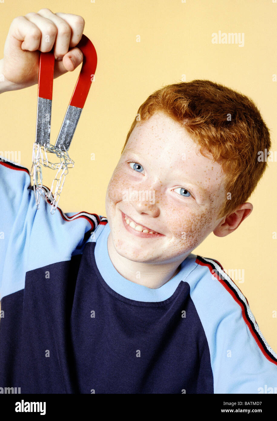 Magnet. Nine year old boy lifting paper clips with a horseshoe magnet ...