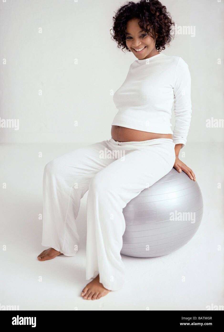 Pregnant woman sitting on a large inflatable rubber ball, known as a ...