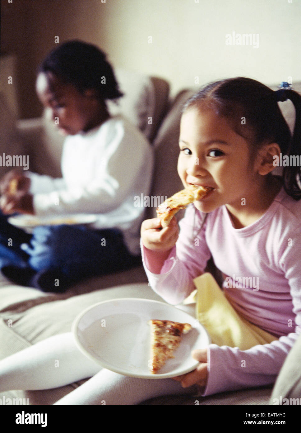 Junk food. Five-year-old girl taking a bite from a slice of pizza. In ...
