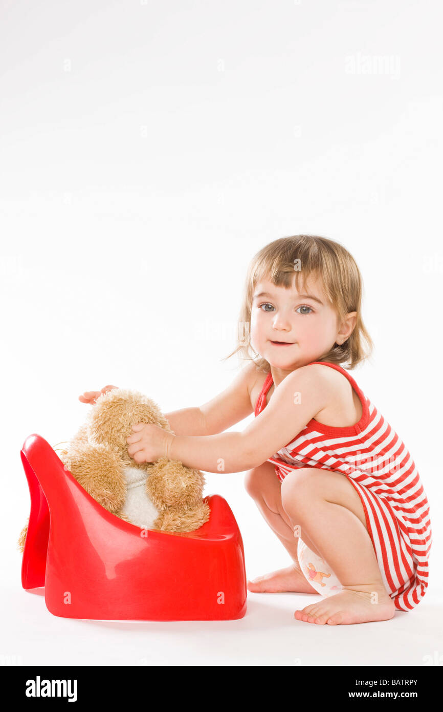 baby girl putting on potty teddy bear Stock Photo - Alamy
