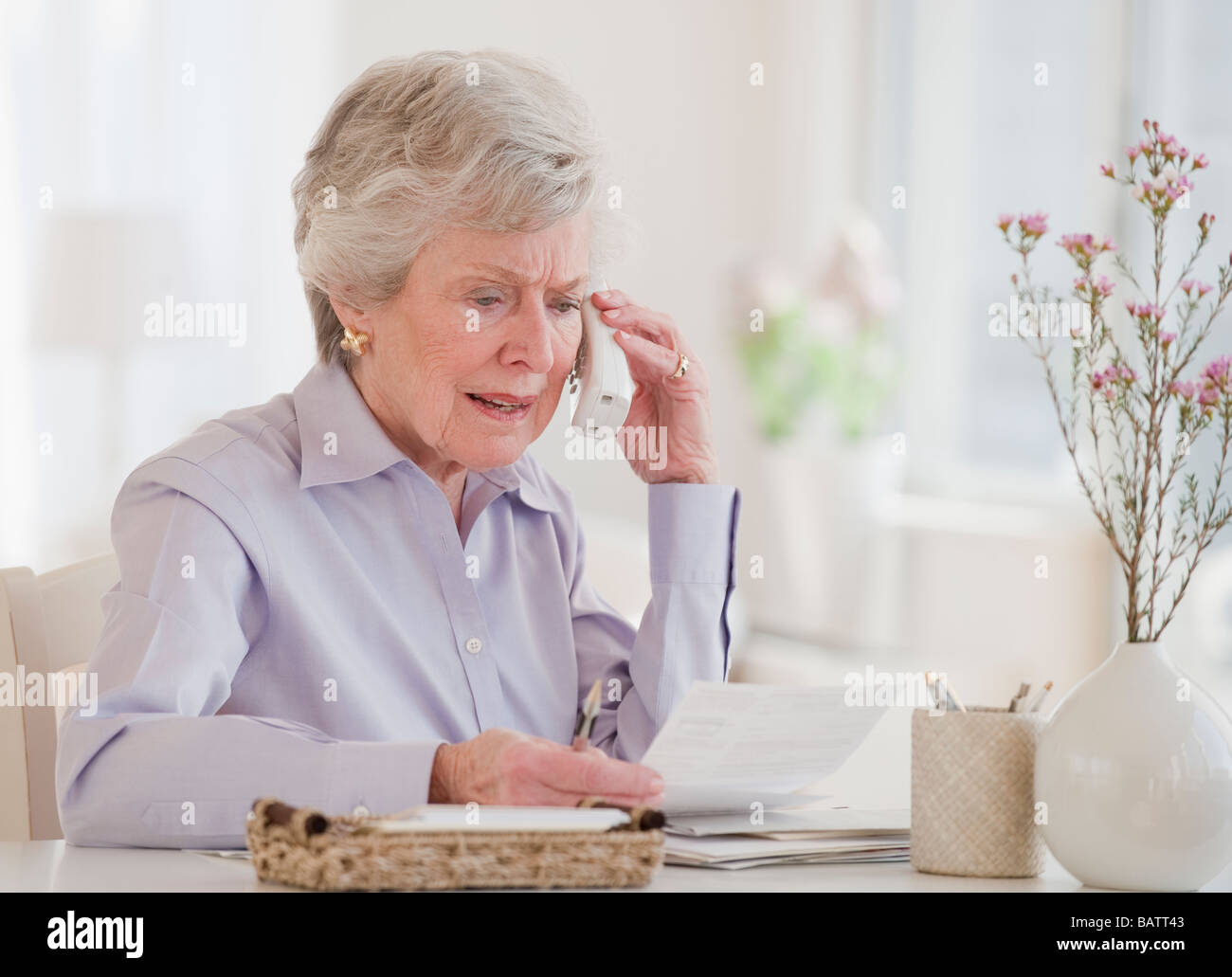 Senior woman paying bills and talking on phone Stock Photo - Alamy