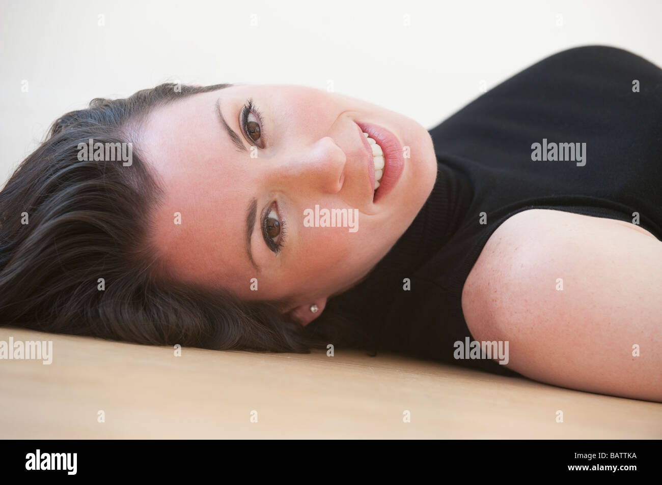 Studio portrait of woman lying on floor Stock Photo - Alamy