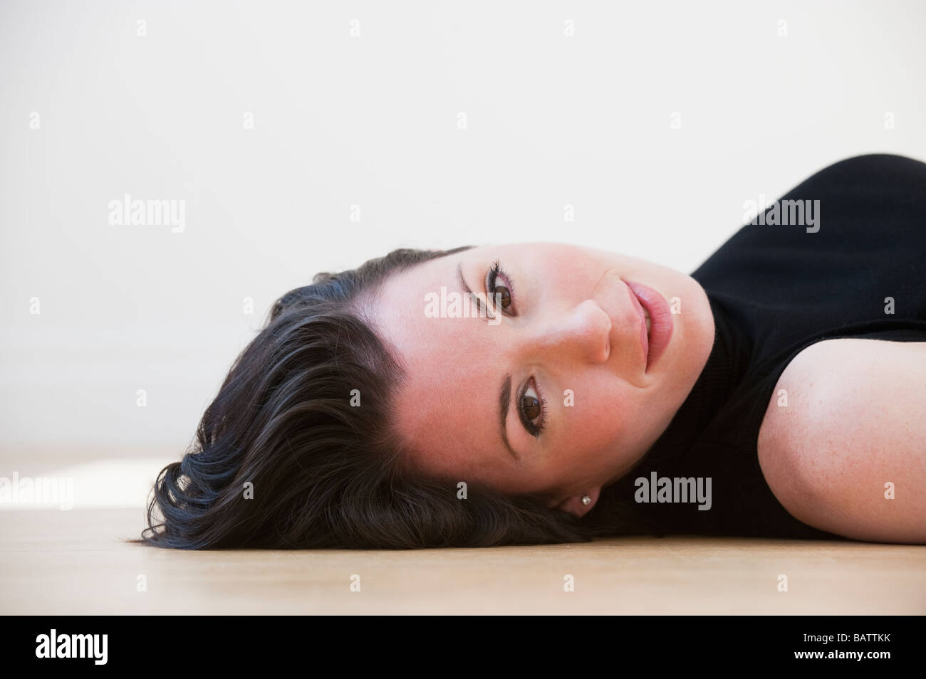 Studio portrait of woman lying on floor Stock Photo - Alamy