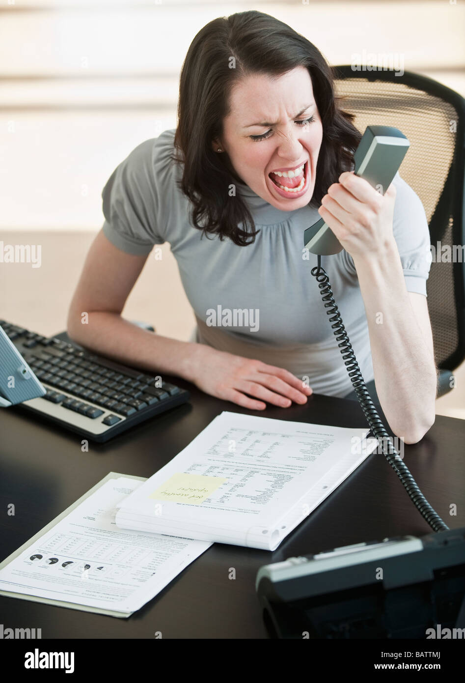 Stressed business woman using telephone in office Stock Photo - Alamy