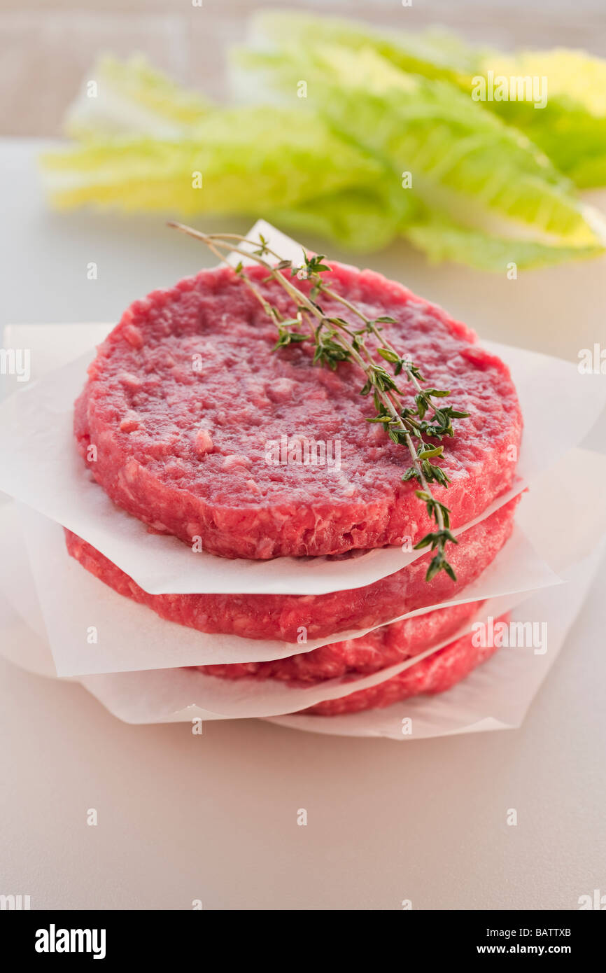 Hamburger patties in stack with salad leaves in background Stock Photo ...