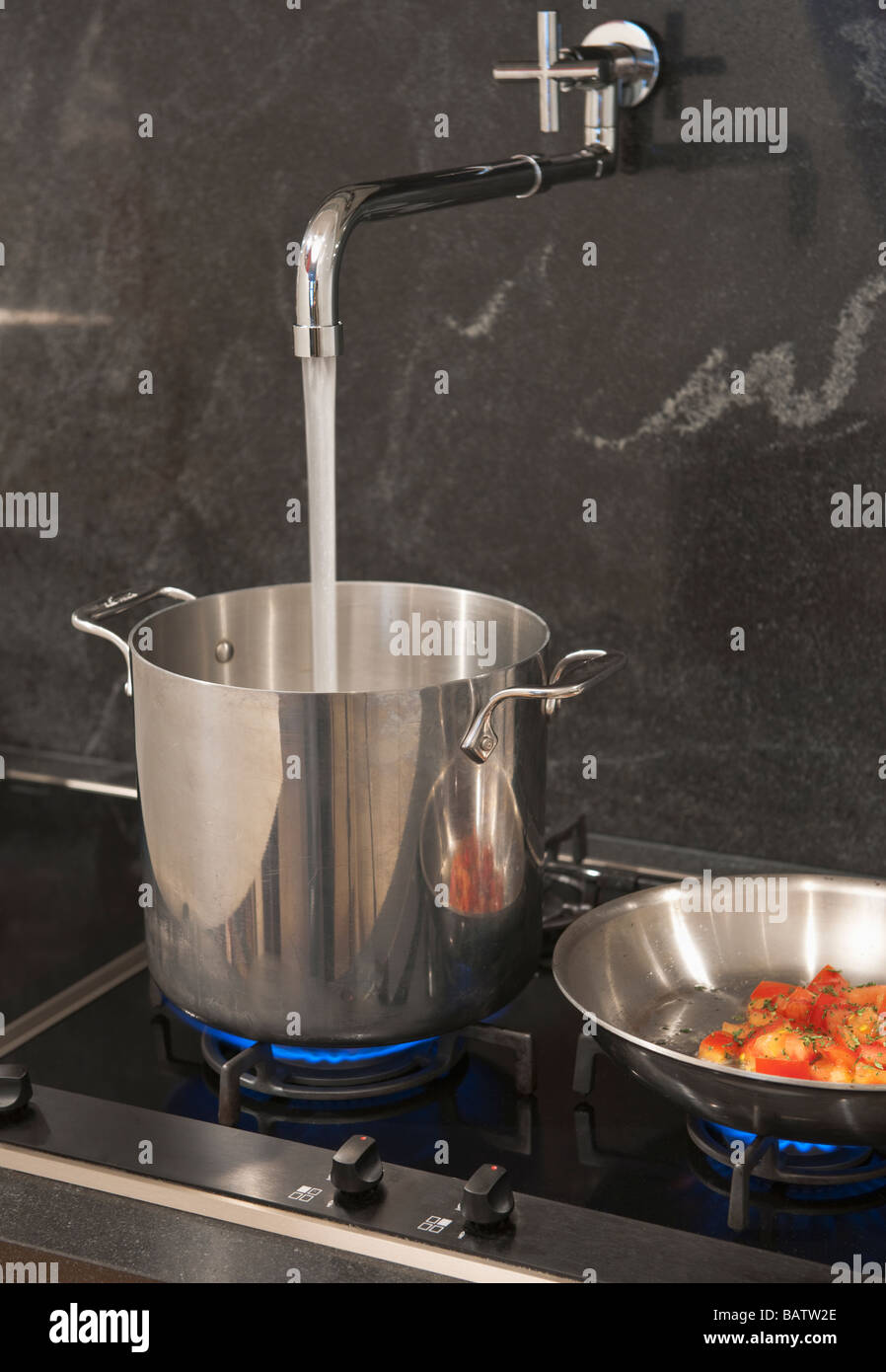 Water pouring from tap into pot Stock Photo - Alamy