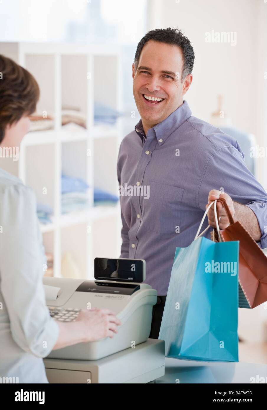 Man at checkout counter with bags Stock Photo - Alamy
