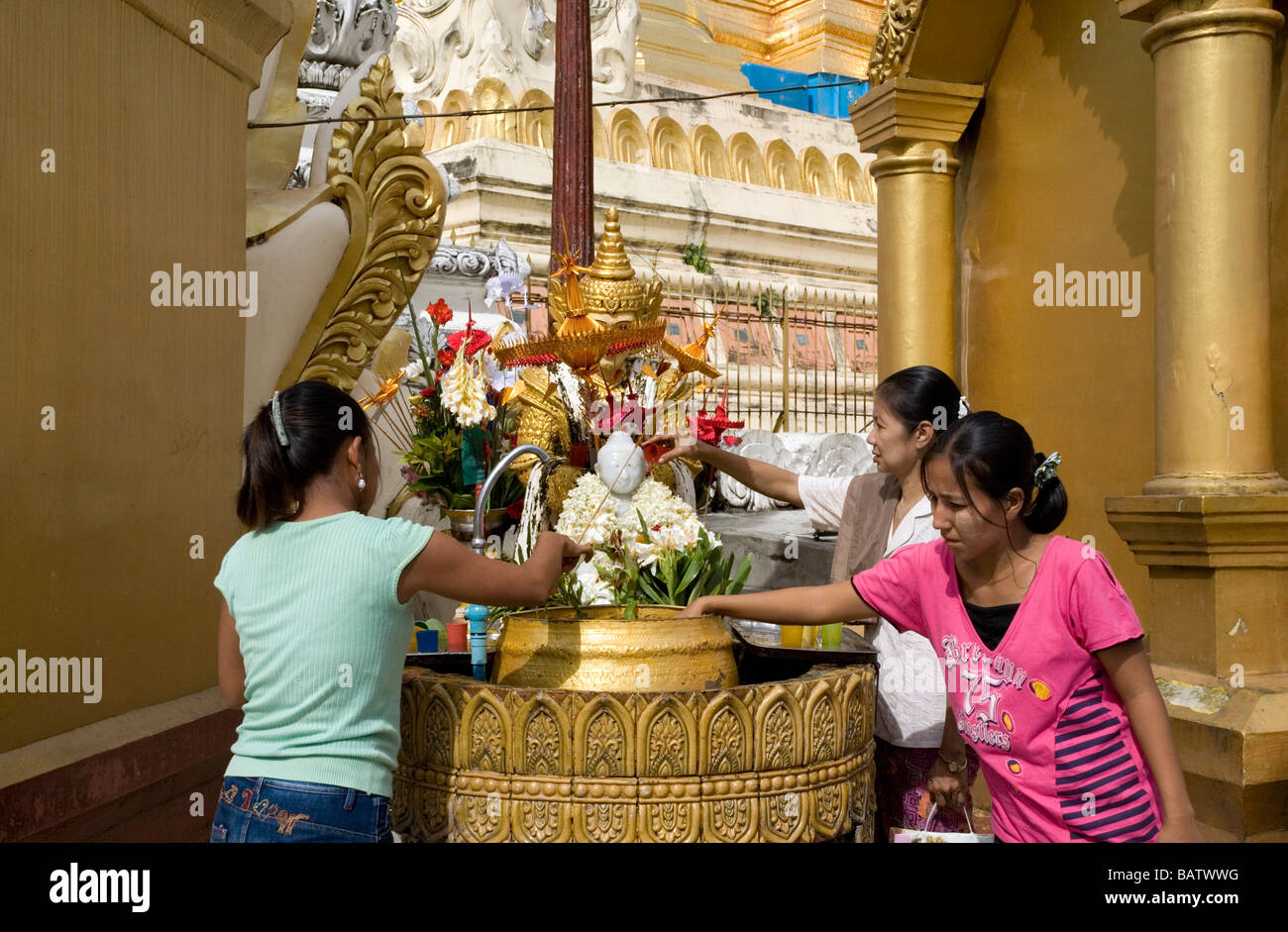Women making a water offering at a Planetary post. Shwedagon Paya ...