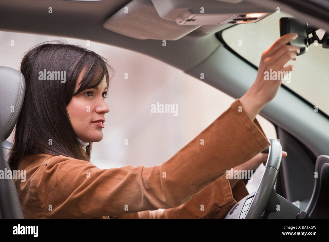 Woman adjusting rear view mirror Stock Photo - Alamy