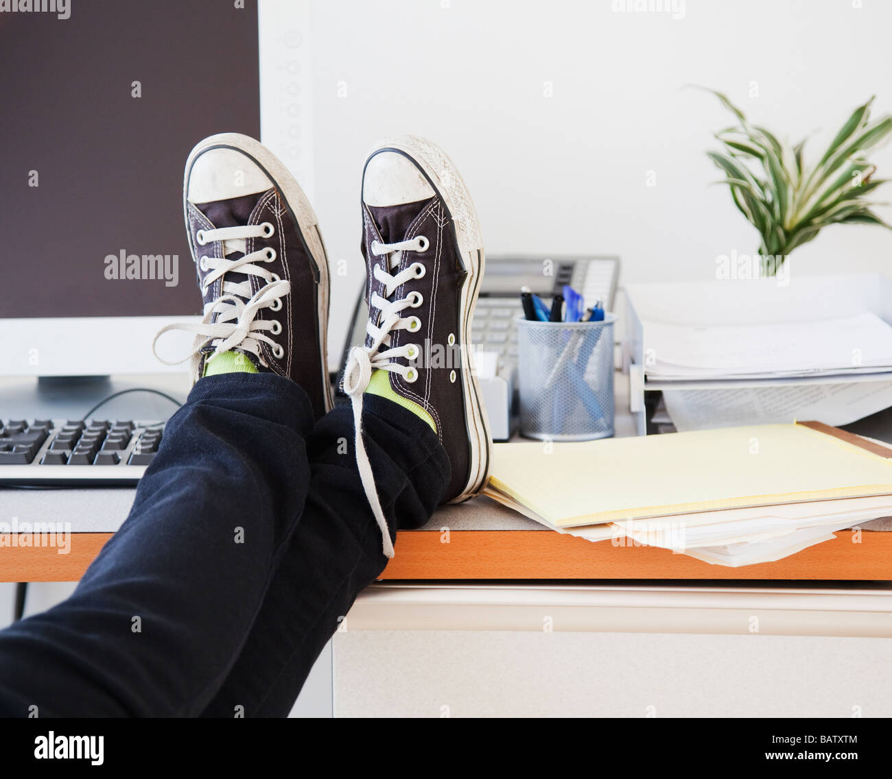 Young office worker in casual clothes relaxing in office with legs on ...