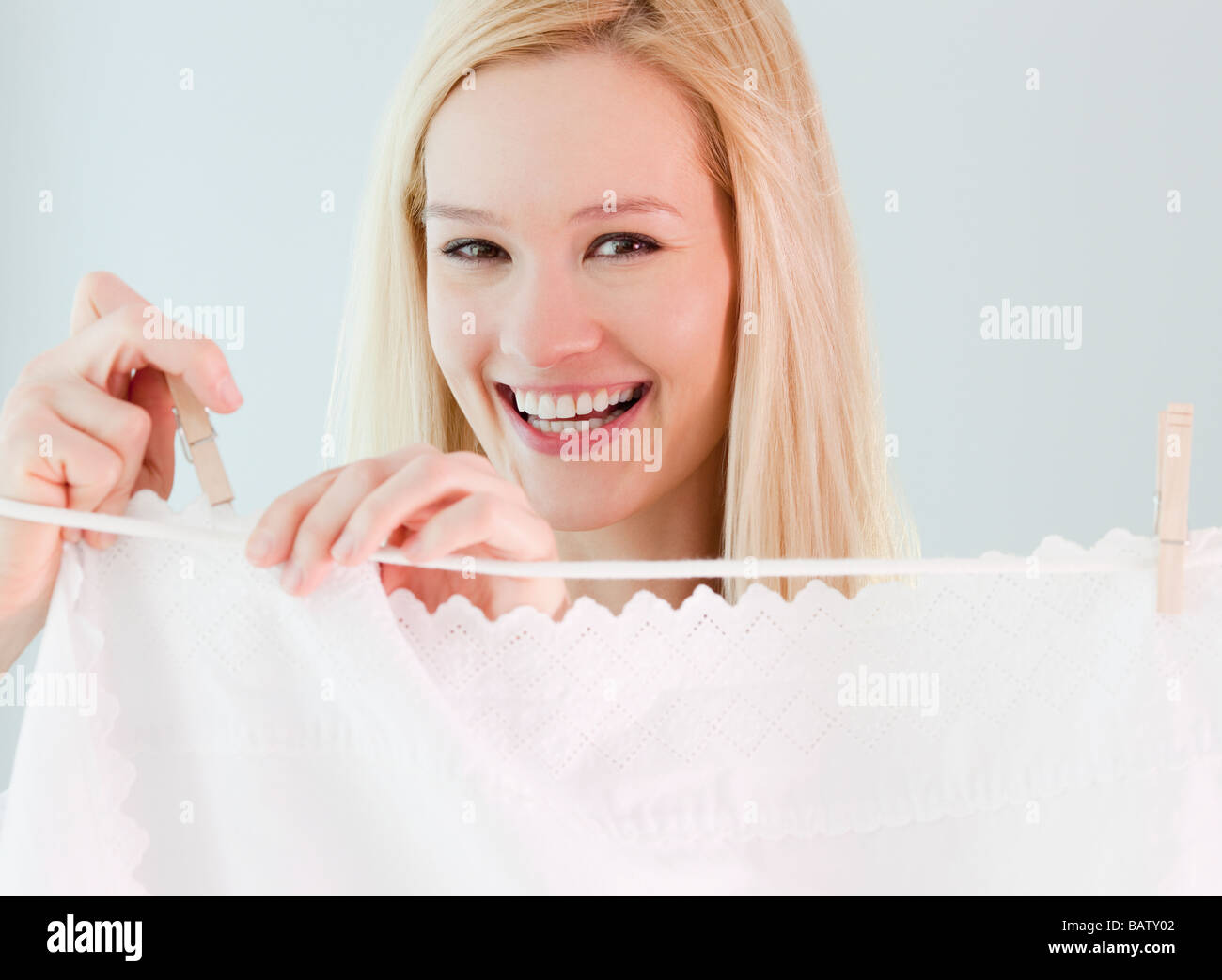Portrait of young woman hanging laundry on washing line Stock Photo - Alamy