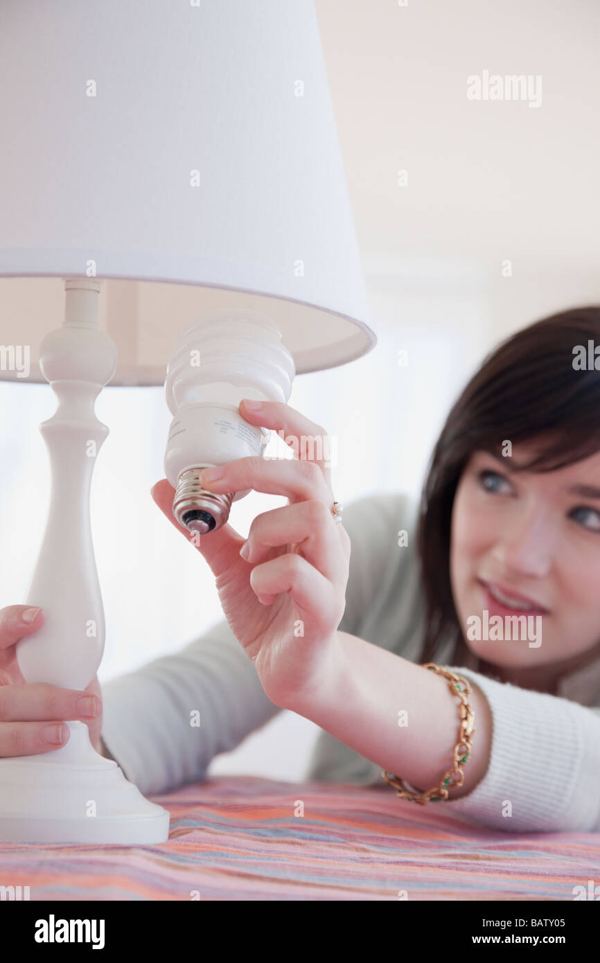 Young woman changing light bulb Stock Photo - Alamy