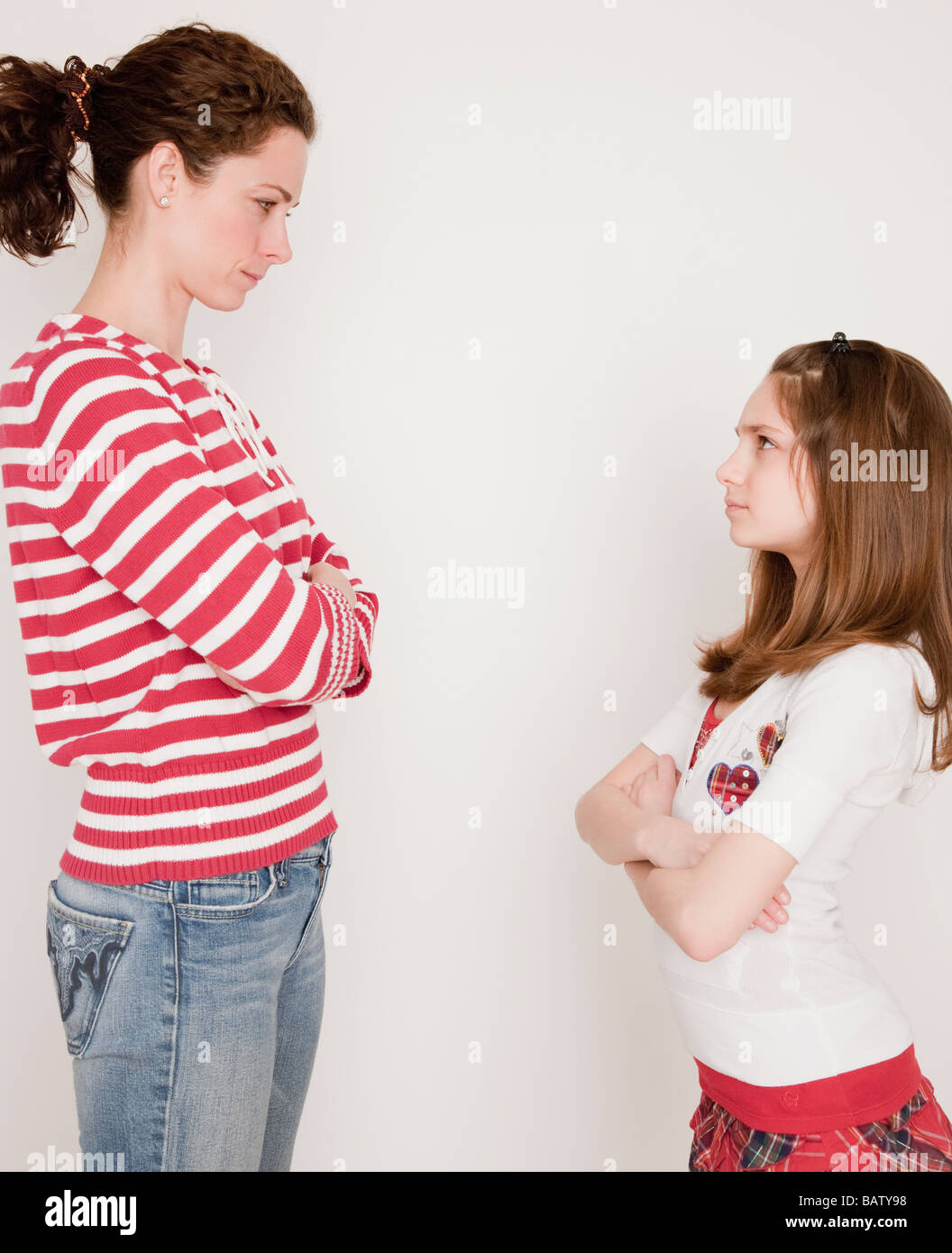 Mother and daughter (10-11 years) having argument, standing face to ...