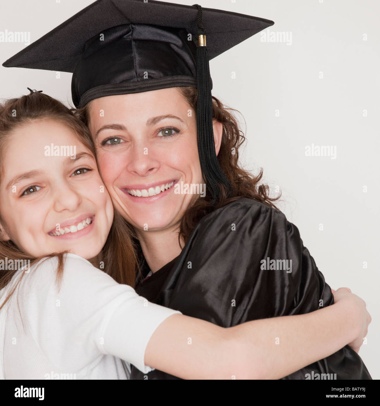 Daughter (10-11 years) embracing mother after her graduation, smiling ...