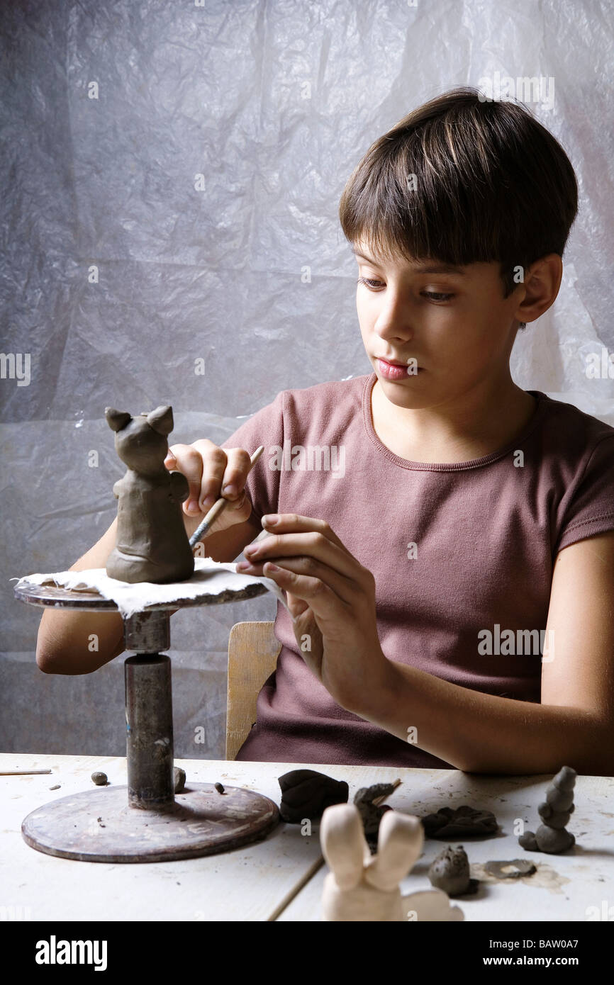 young boy forming little sculpture out of clay Stock Photo - Alamy