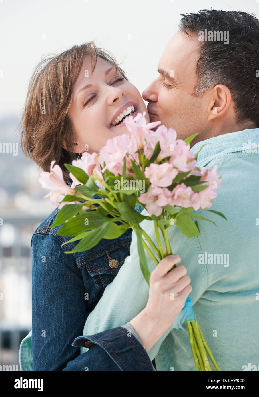 Couple embracing, woman holding flowers Stock Photo - Alamy