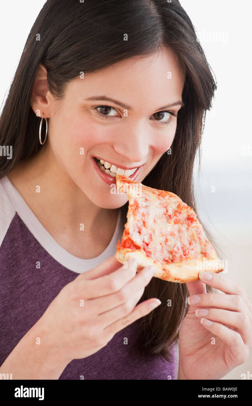 Portrait of woman eating pizza slice Stock Photo - Alamy