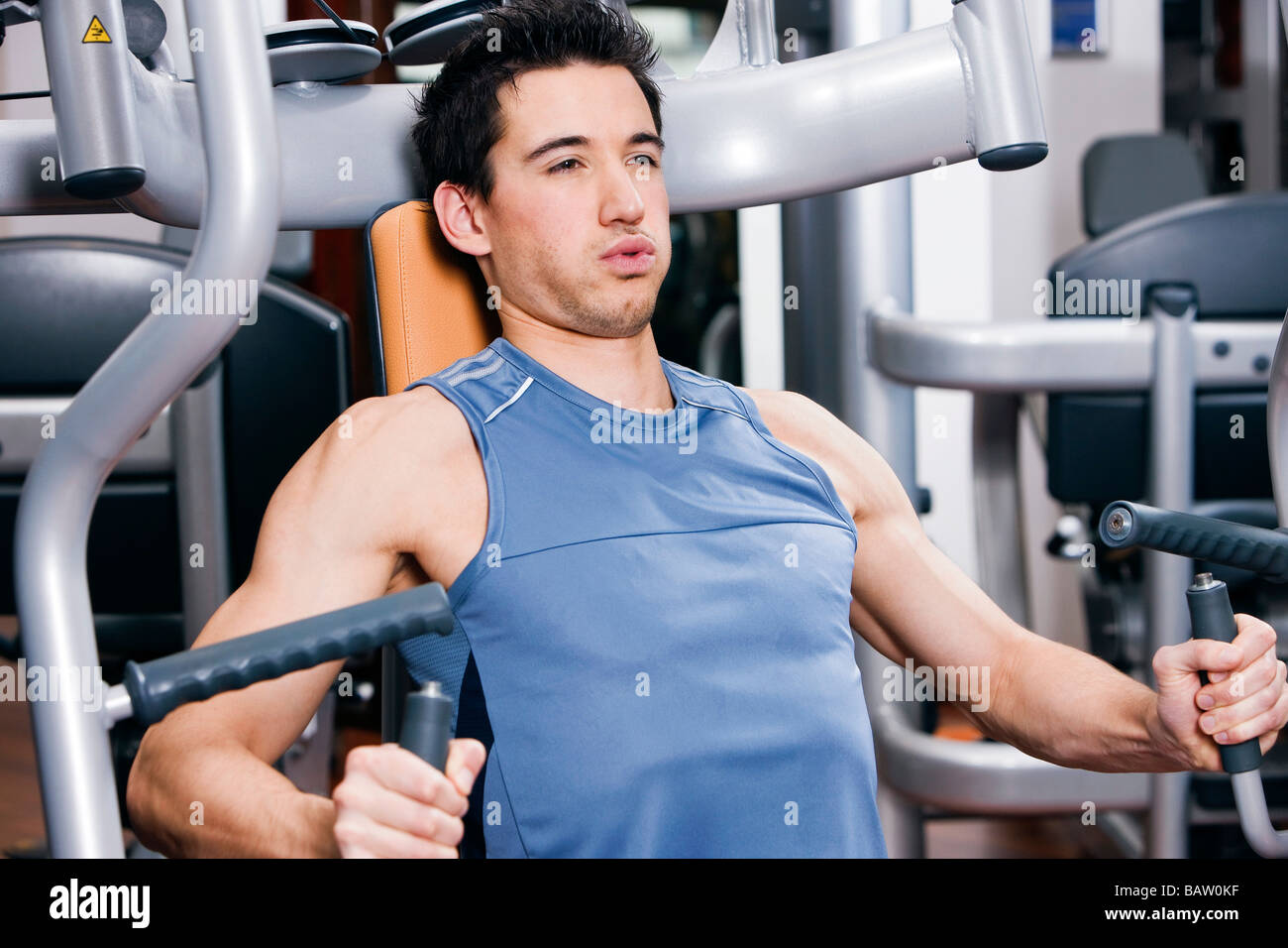 portrait of young man exercising with weight machine Stock Photo - Alamy