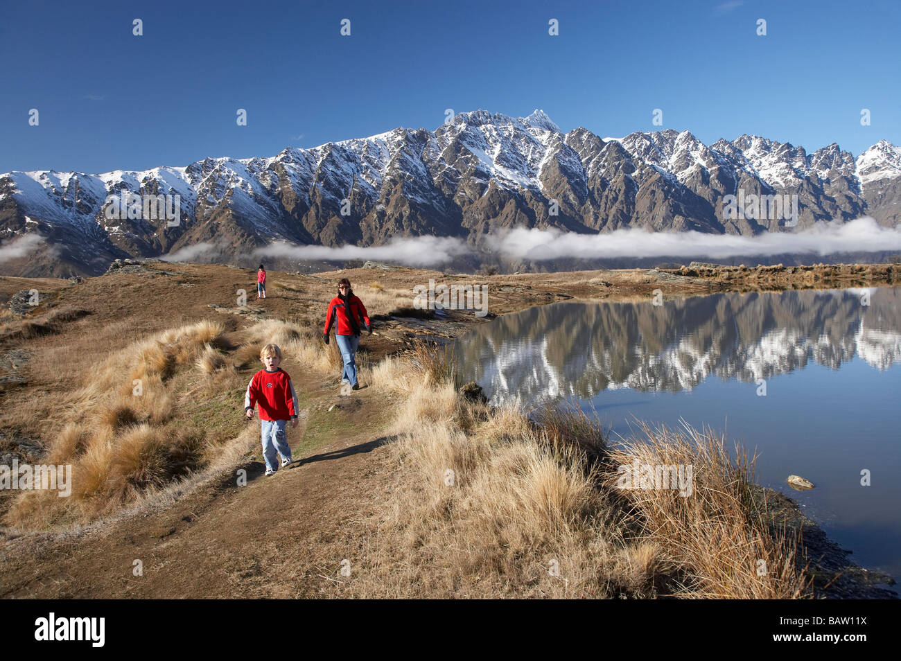 Family Walking and The Remarkables reflected in Summit Tarn Deer Park ...