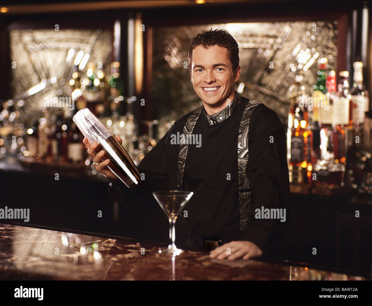 Young man standing behind bar shaking cocktail shaker, portrait Stock ...