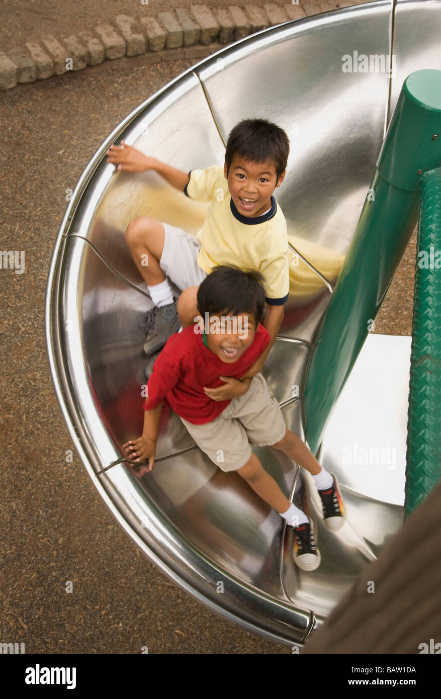 Asian boys sliding down circular slide Stock Photo - Alamy