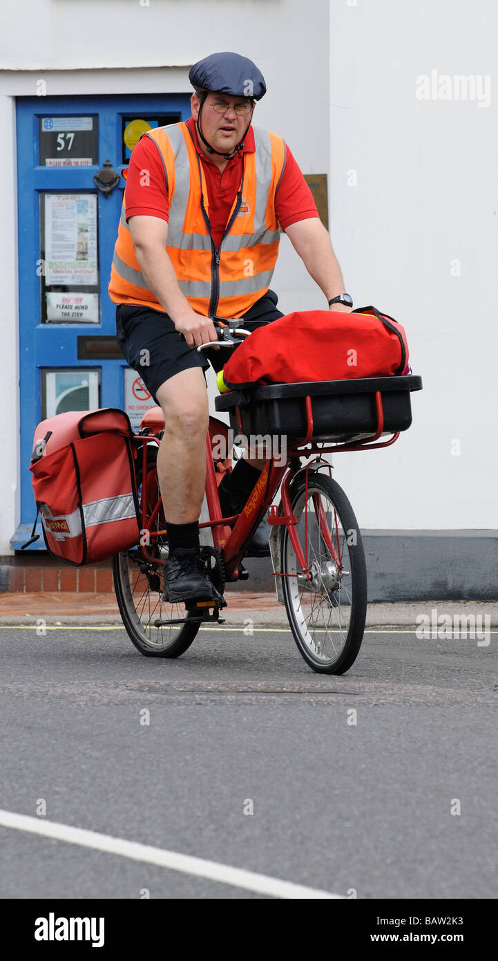 Postman cycling on his Royal Mail route wearing protective headgear ...
