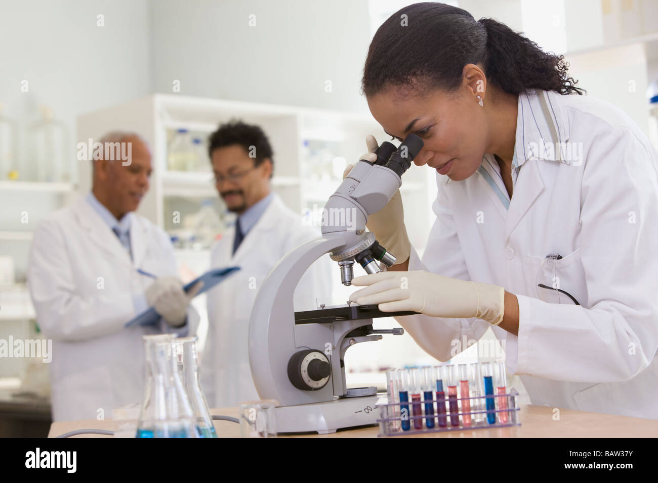 African scientist performing analysis in laboratory with microscope ...