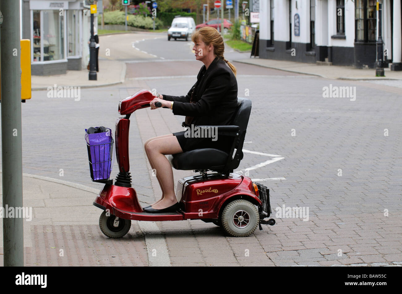 Woman seated on a Rascal mobility scooter crosses the road at a ...