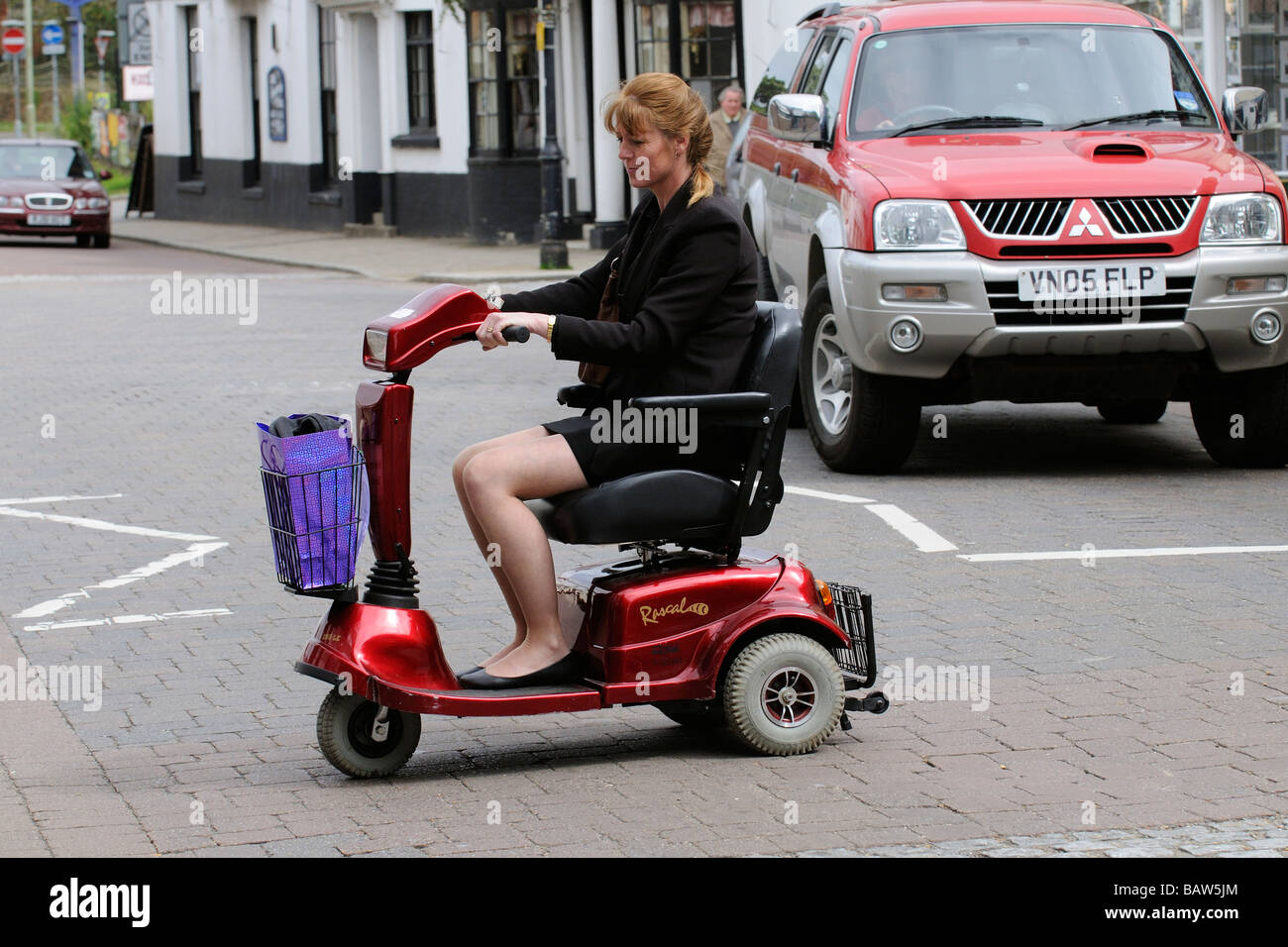 Woman seated on a Rascal mobility scooter crosses the road at a ...
