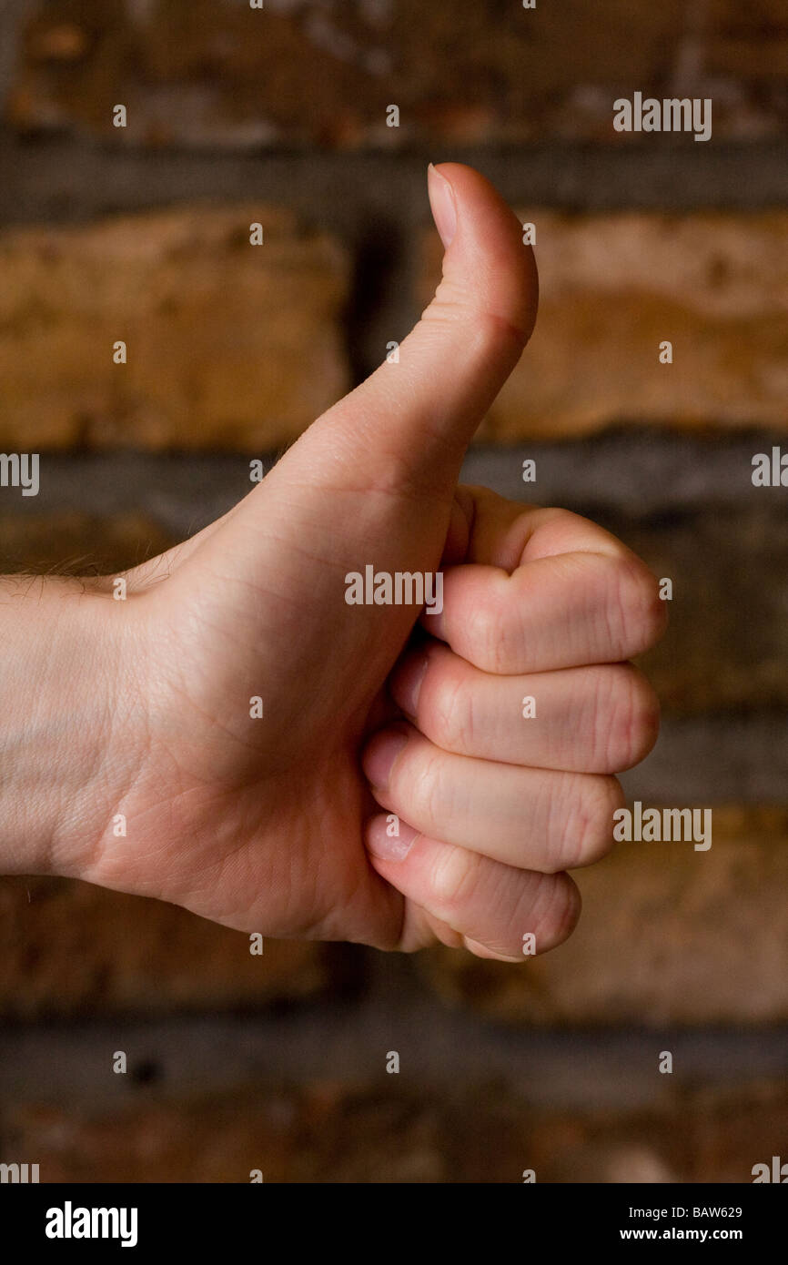 thumb up on brick wall background Stock Photo - Alamy