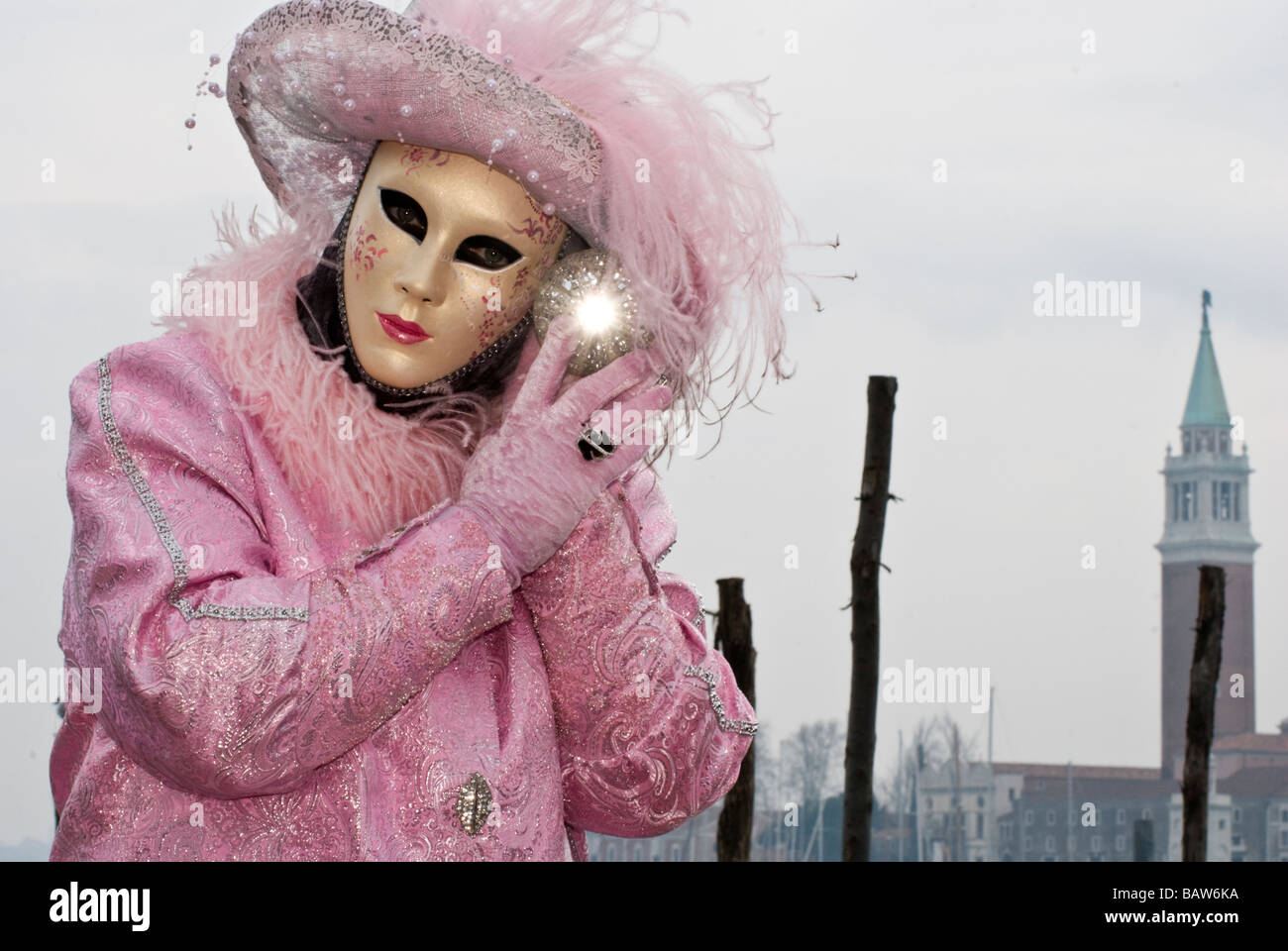 Single girl in a Venetian carnival disguise with pink color hanging a ...