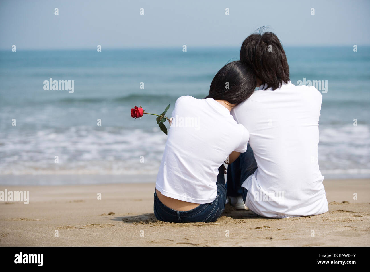 Young woman leaning head on young man s shoulder sitting on beach Stock ...