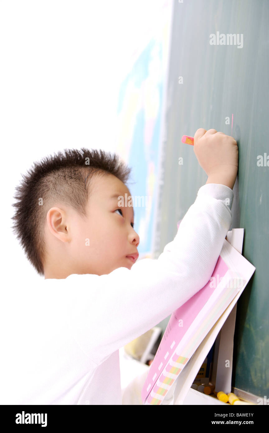 Boy writing down answers on blackboard Stock Photo - Alamy