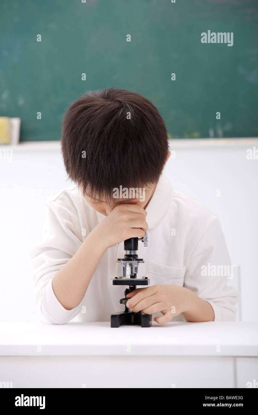 Boy looking through microscope front view Stock Photo - Alamy