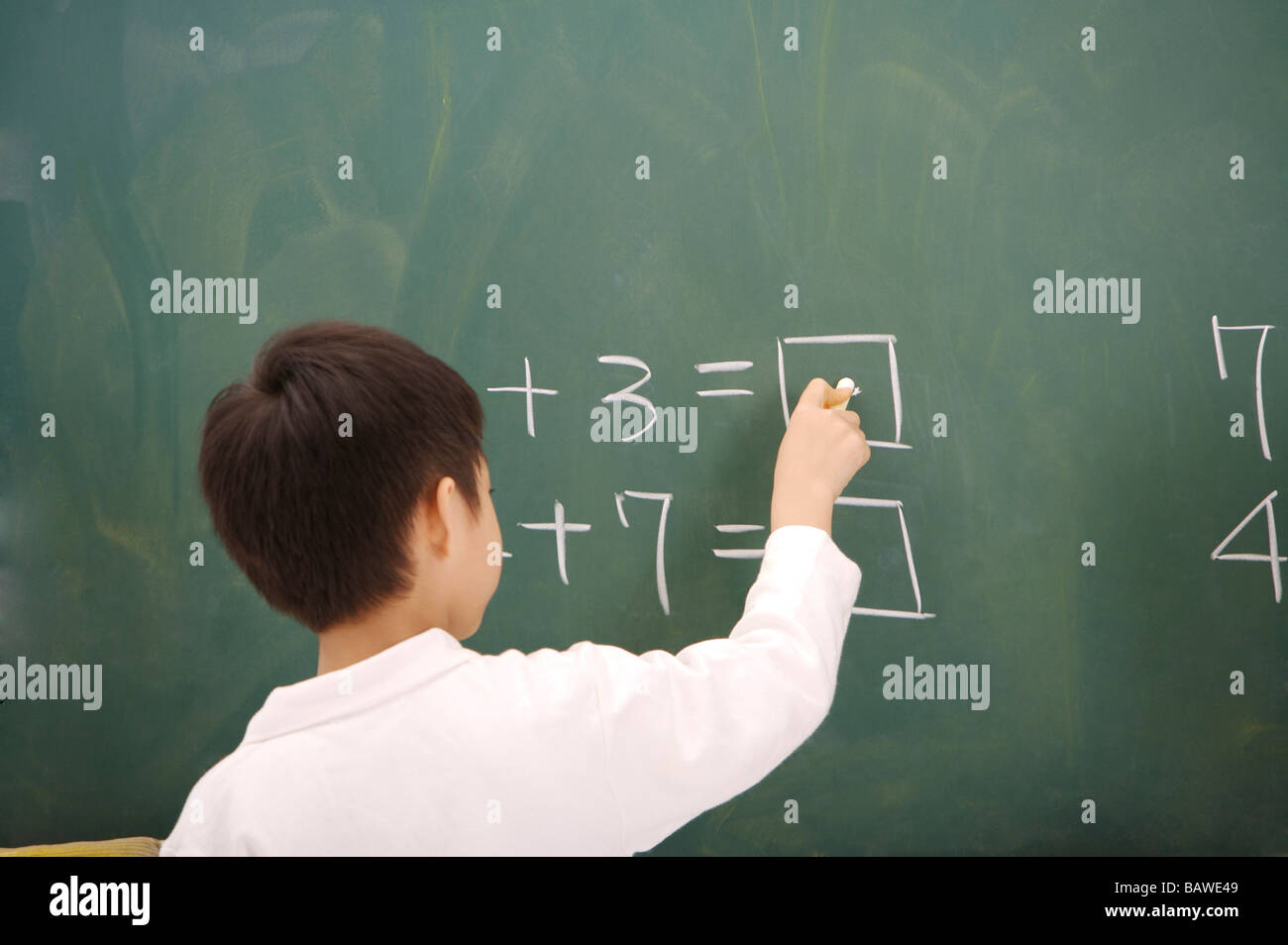 Boy solving mathematical equation on blackboard rear view Stock Photo ...