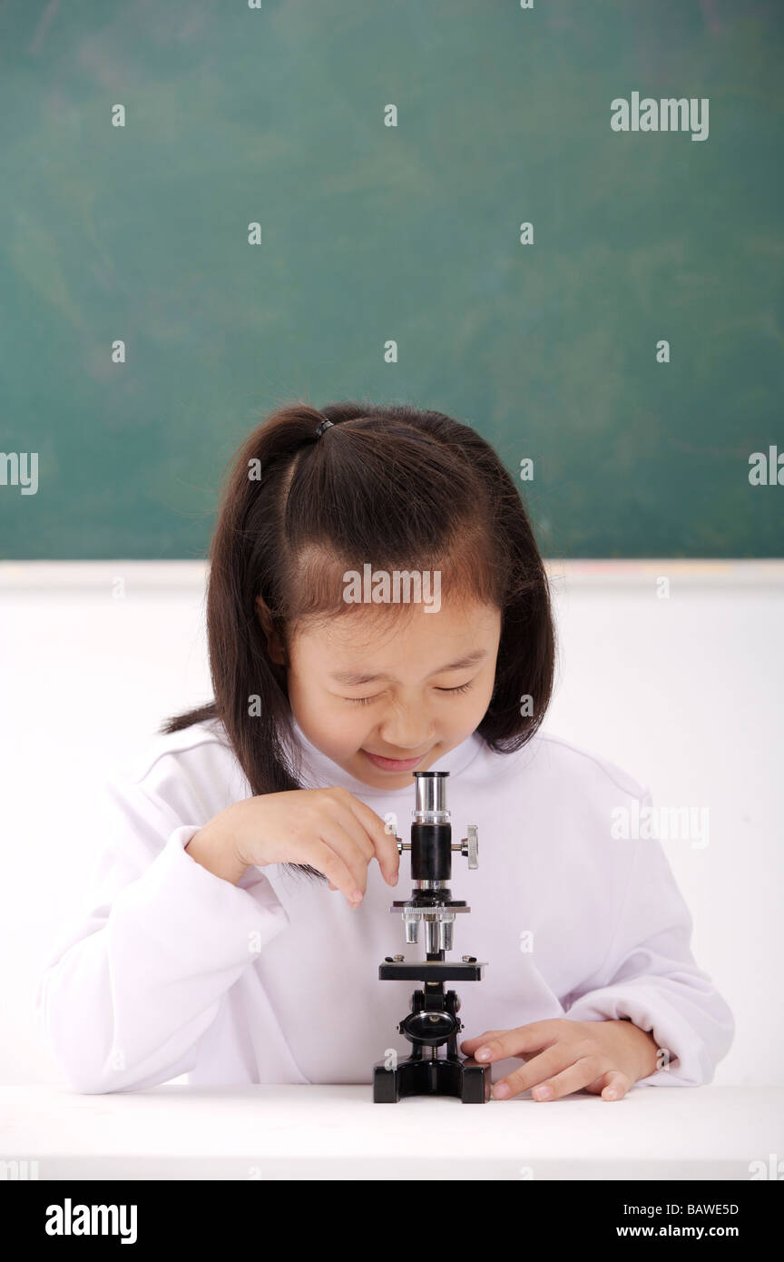 Girl looking through microscope Stock Photo - Alamy