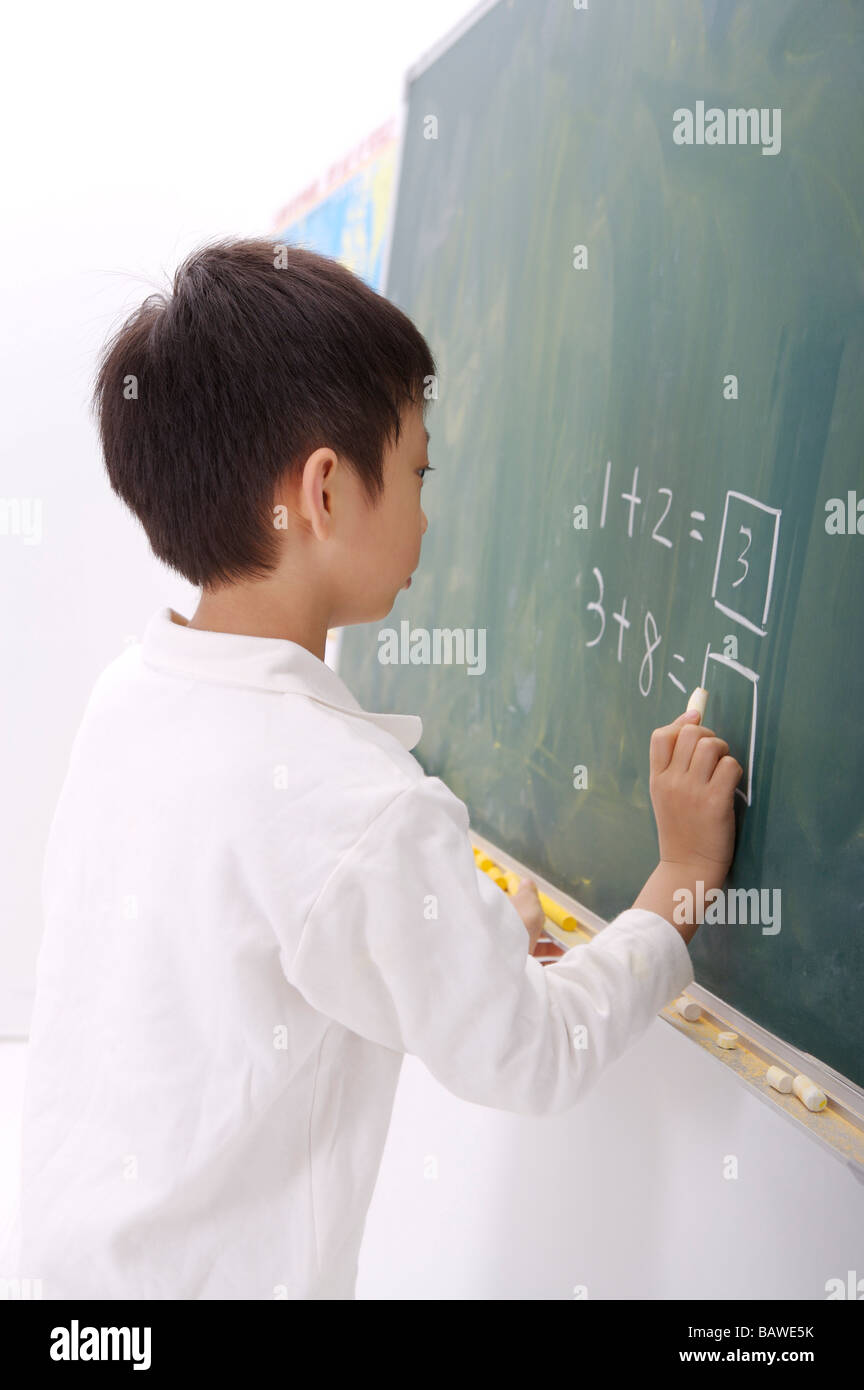 Boy solving mathematical equation on blackboard side view Stock Photo ...