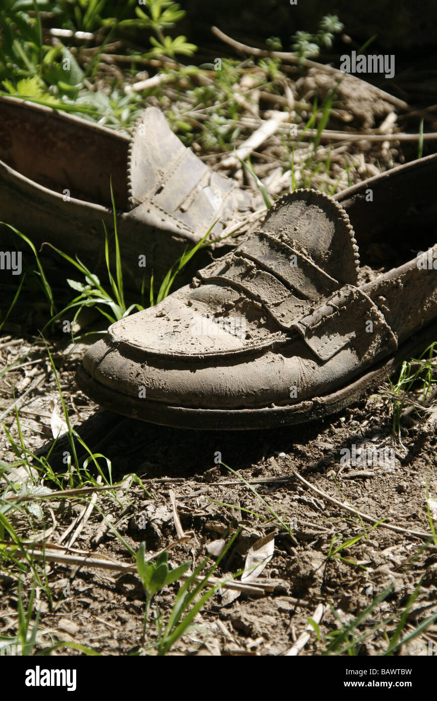 a pair of brown shoes covered with mud in field Stock Photo - Alamy