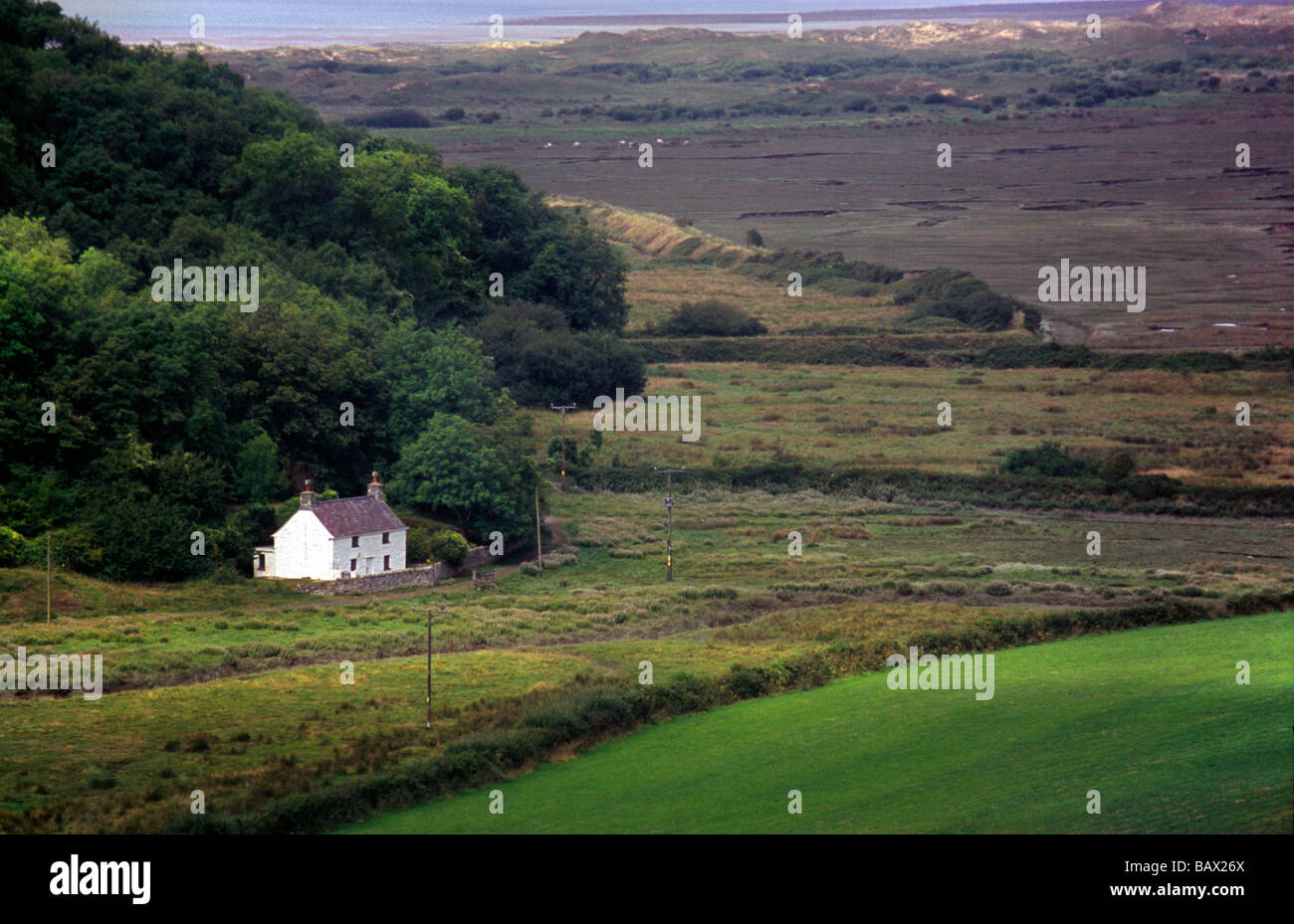 Lone cottage at the base of a wooded hill at Llanmadoc Gower Peninsula ...