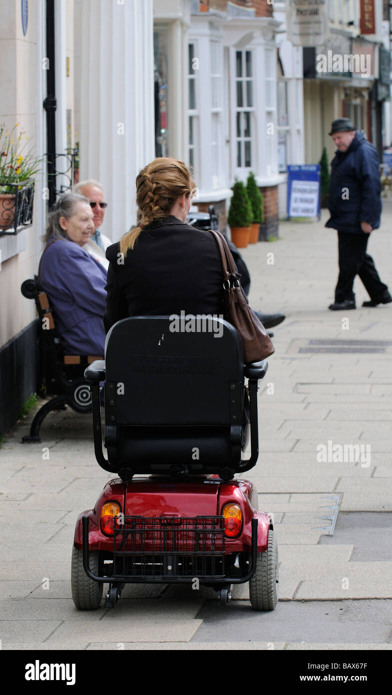 Woman seated on a Rascal mobility scooter driving along the pavement ...